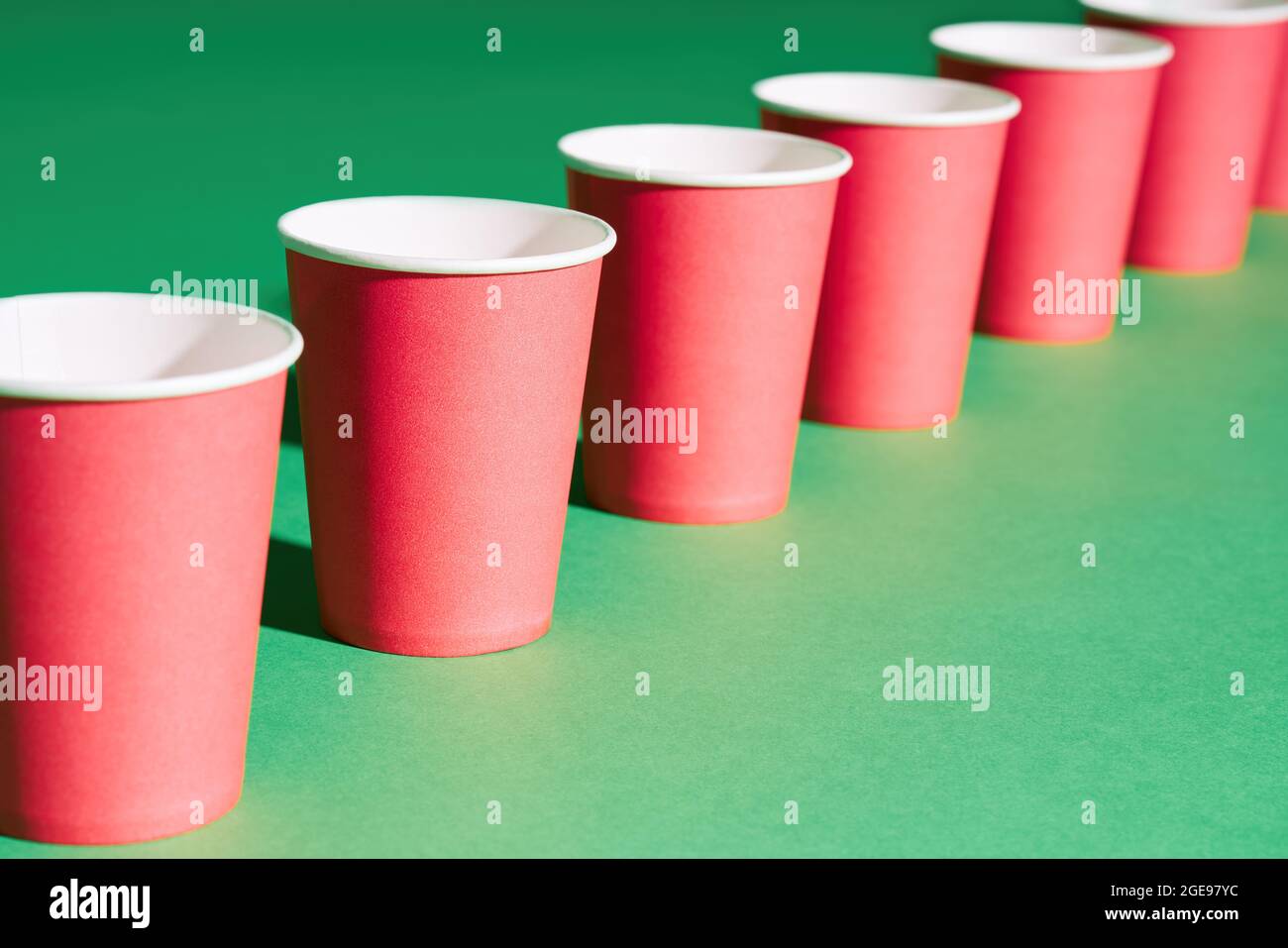 Diminishing perspective of red paper cup in row on green background ...