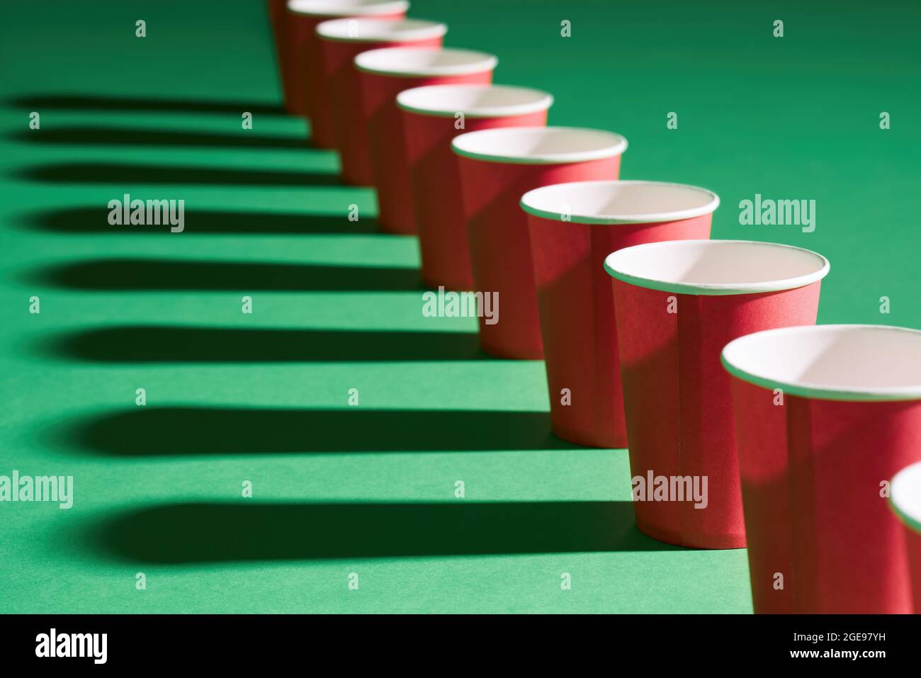 Diminishing perspective of red paper cup in row on green background ...