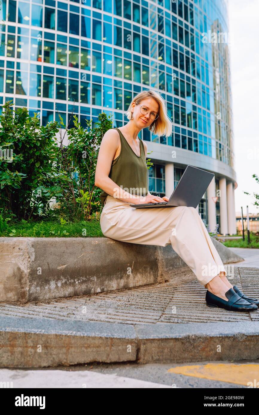 Blonde business woman wearing glasses sit with laptop among the ...