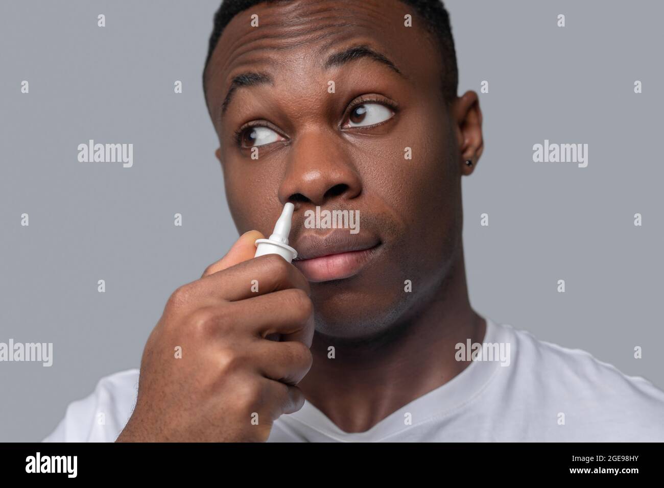 A dark-skinned man dropping drops to his nose Stock Photo - Alamy