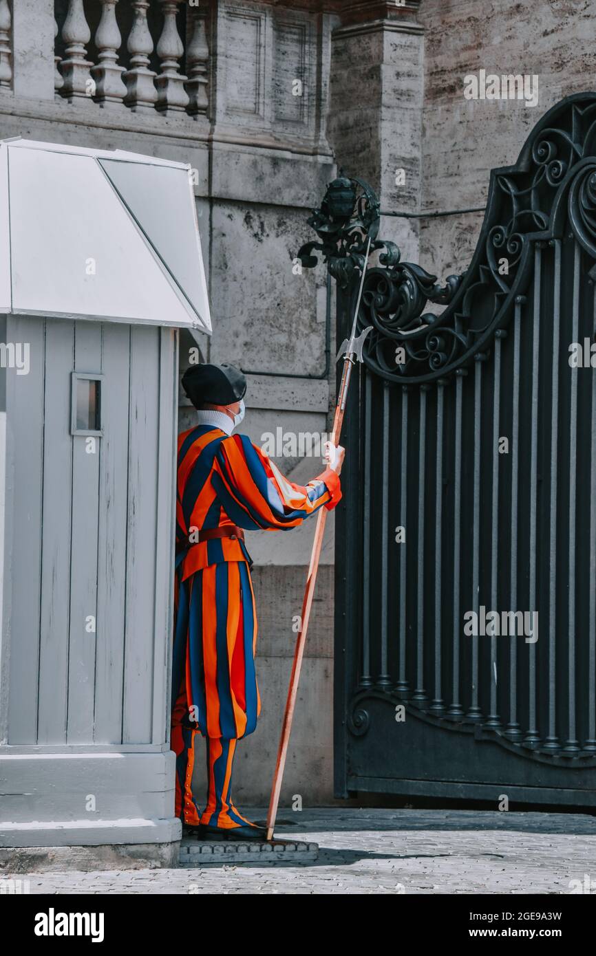 Vertical shot of a Pontifical Swiss Guard standing on post at the St ...