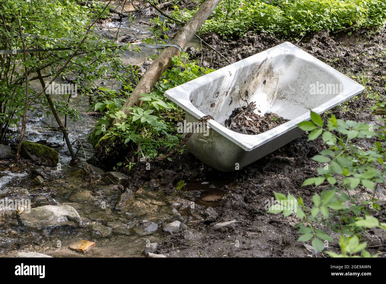 An old tub chained to a tree by a stream. Natural bathroom Stock Photo ...