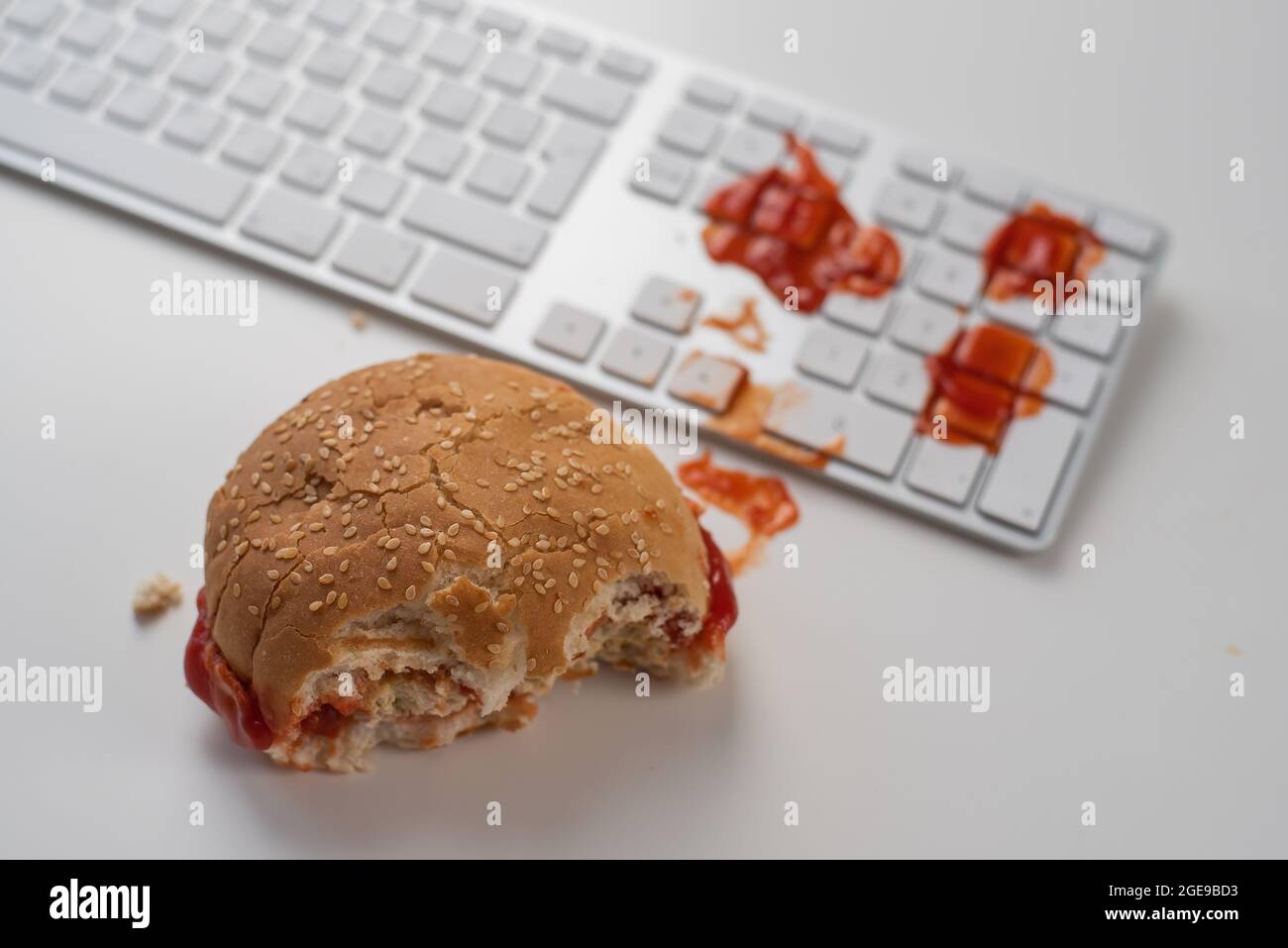Burger and drops of ketchup on computer keyboard on white desktop Stock ...