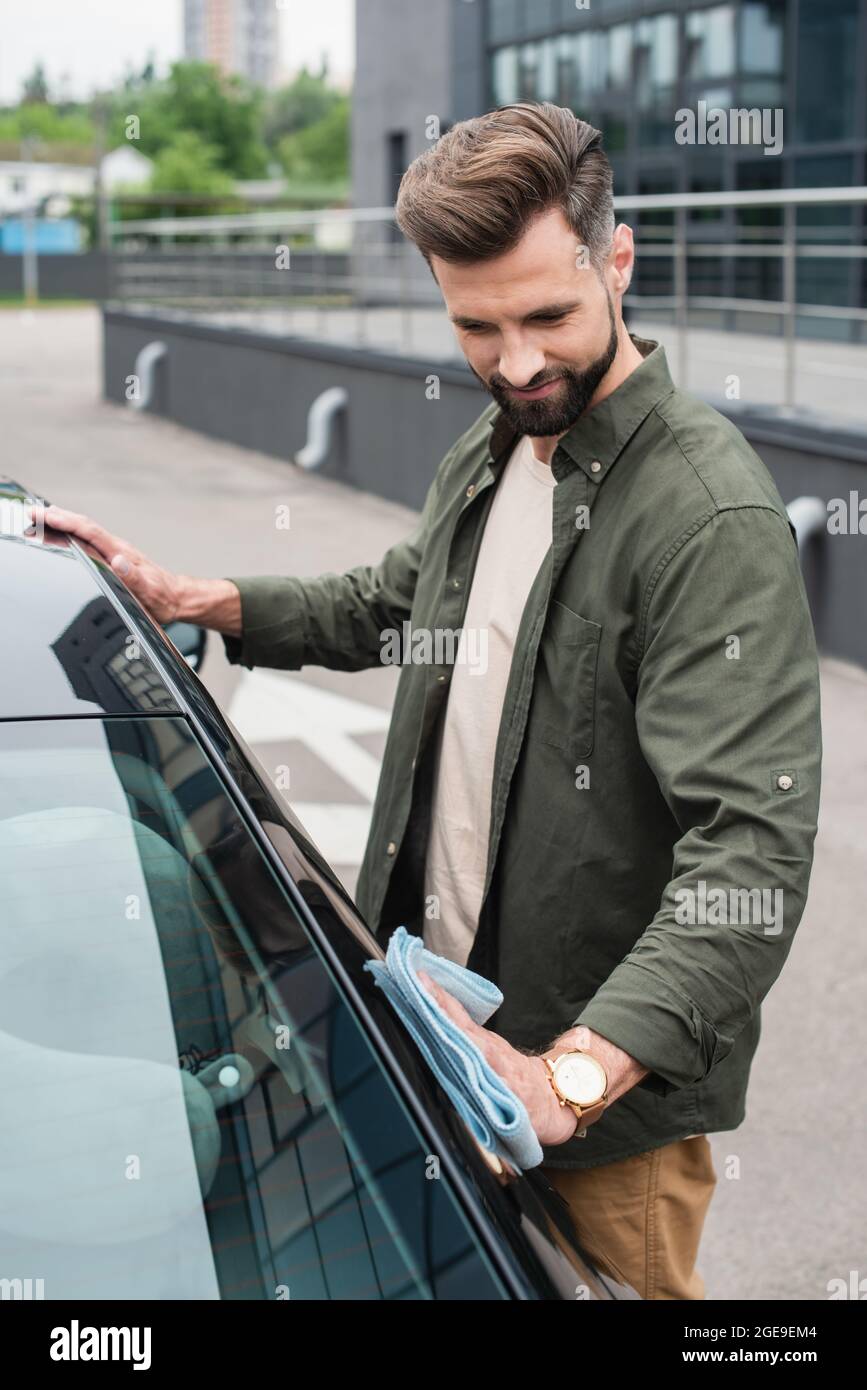 Bearded driver waxing car with rag outdoors Stock Photo - Alamy