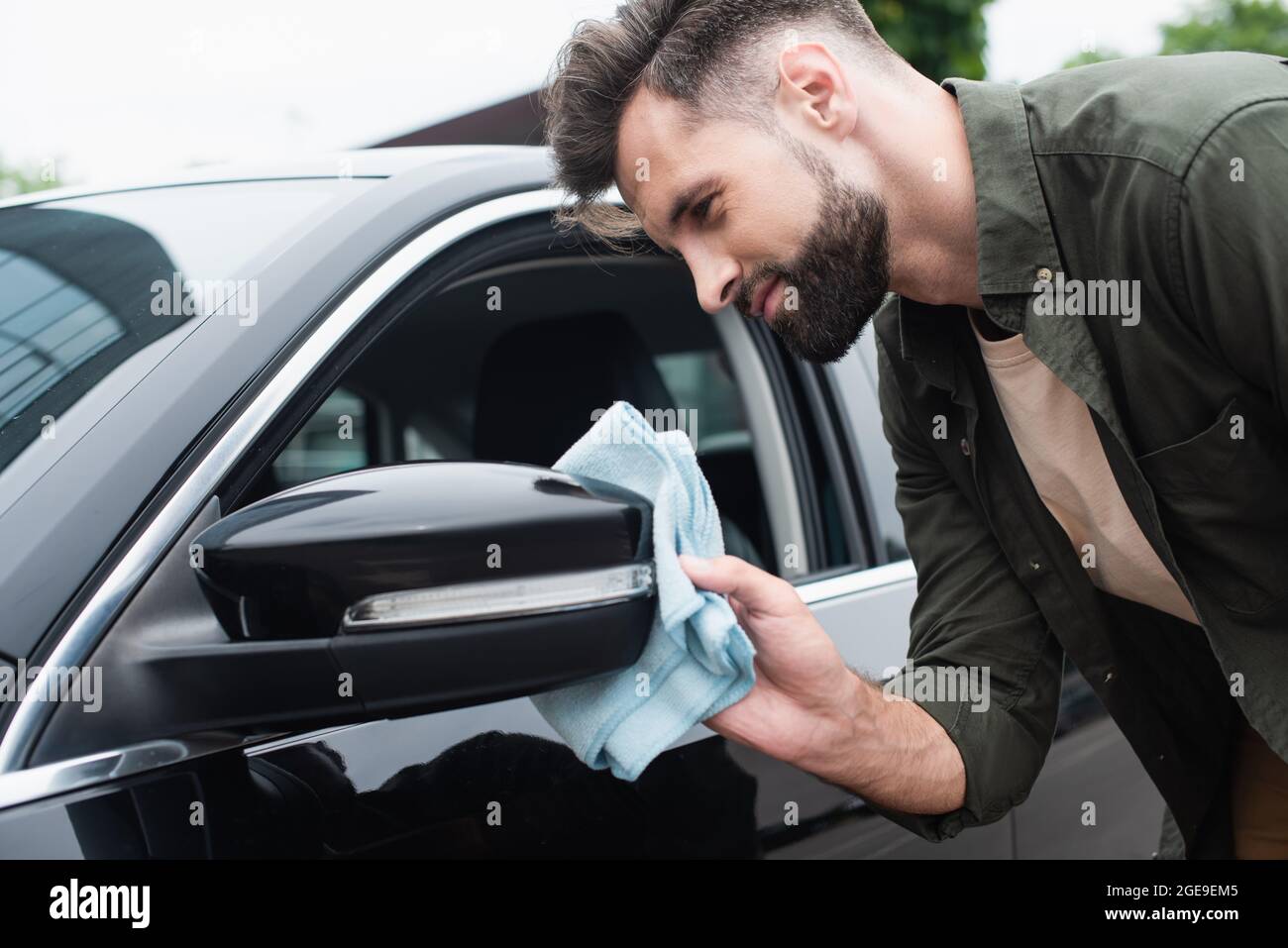 Side view of man with rag cleaning wing mirror of auto Stock Photo - Alamy