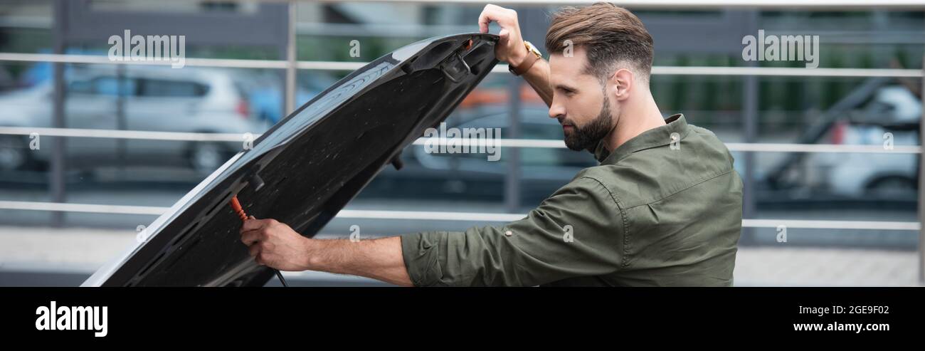 Side view of brunette driver opening car hood outdoors, banner Stock ...