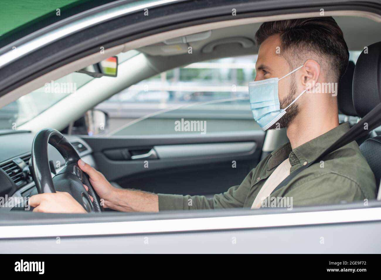 Side view of man in medical mask driving car Stock Photo - Alamy
