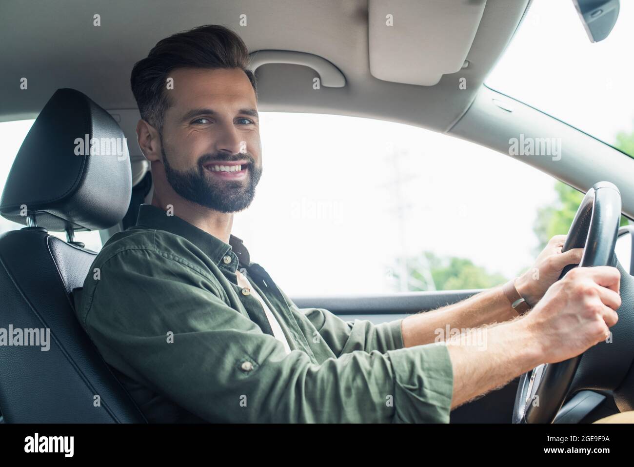 Bearded driver smiling at camera in auto Stock Photo - Alamy