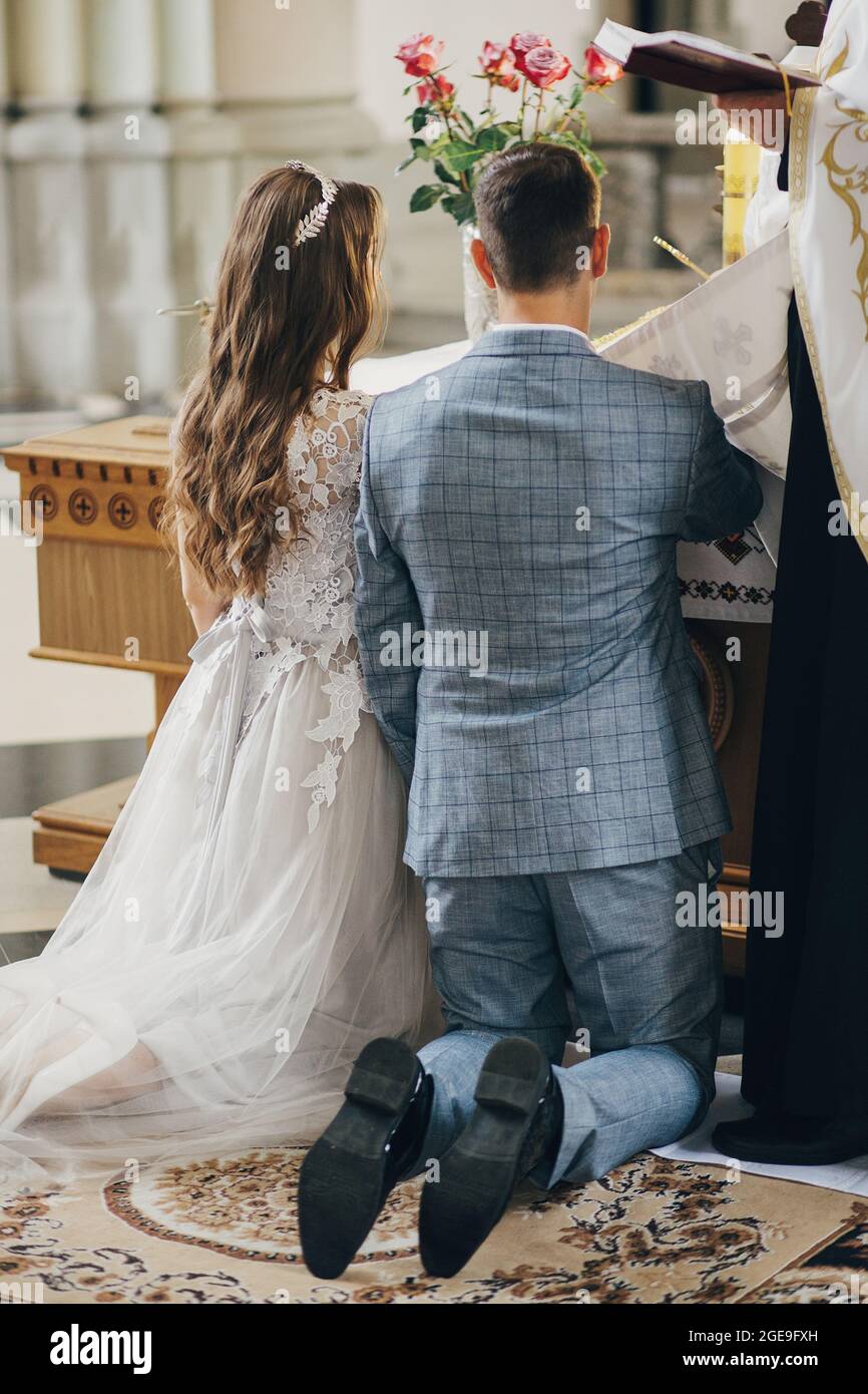 Stylish emotional bride and groom making oaths and holding hands on ...
