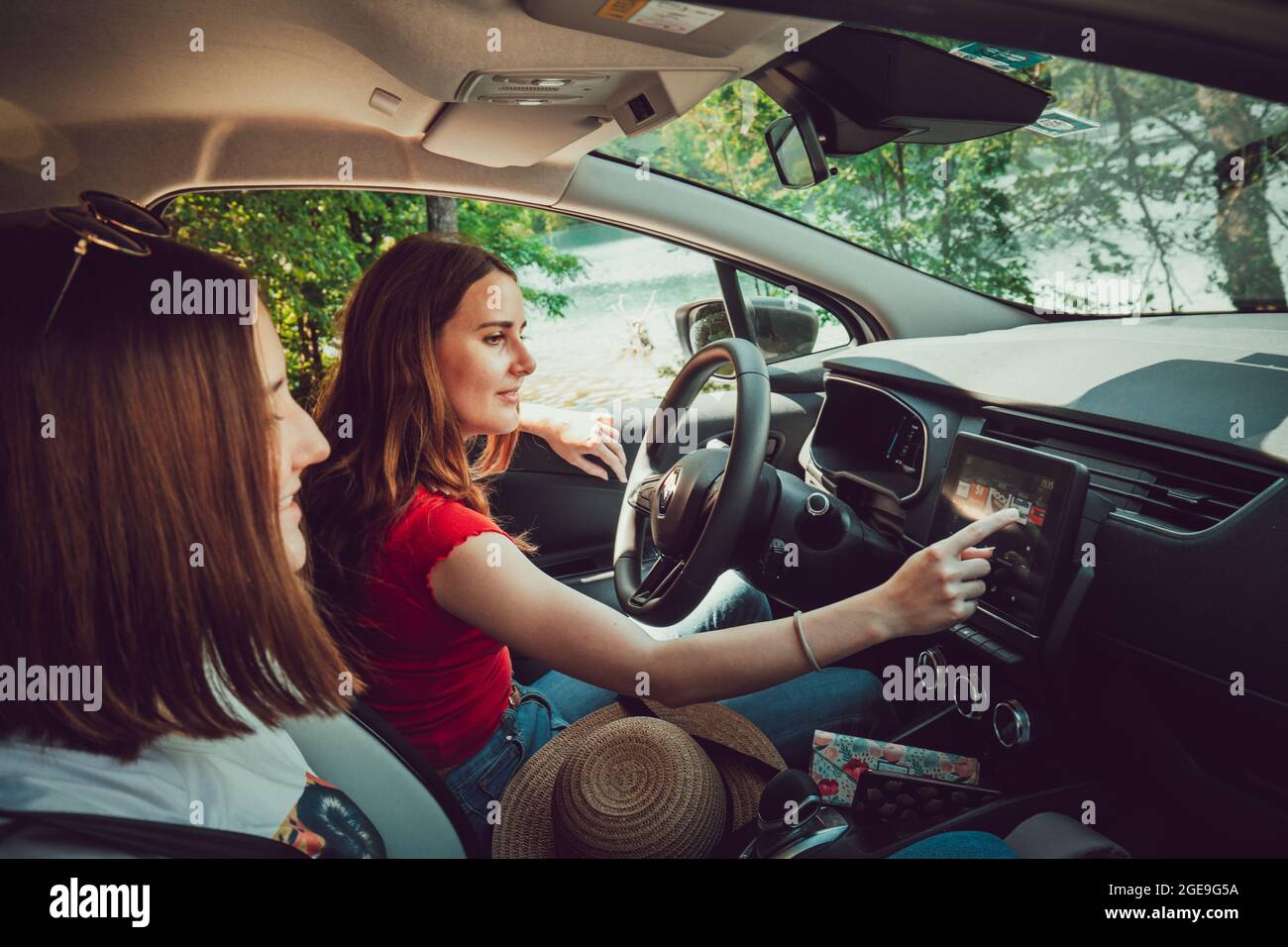 Two young female friends driving, listening to good music in car, enjoy ...