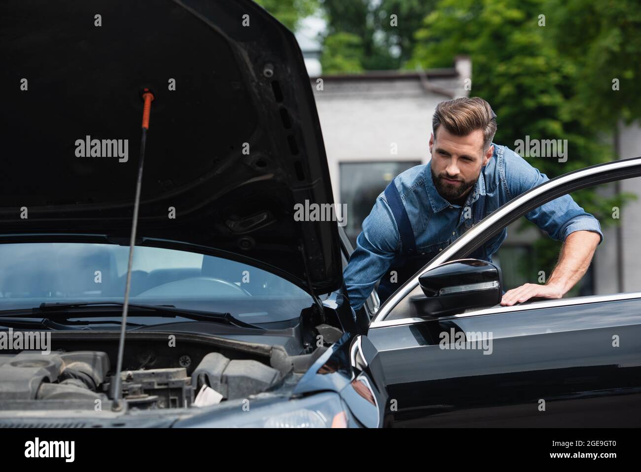 Mechanic standing near door of car outdoors Stock Photo - Alamy