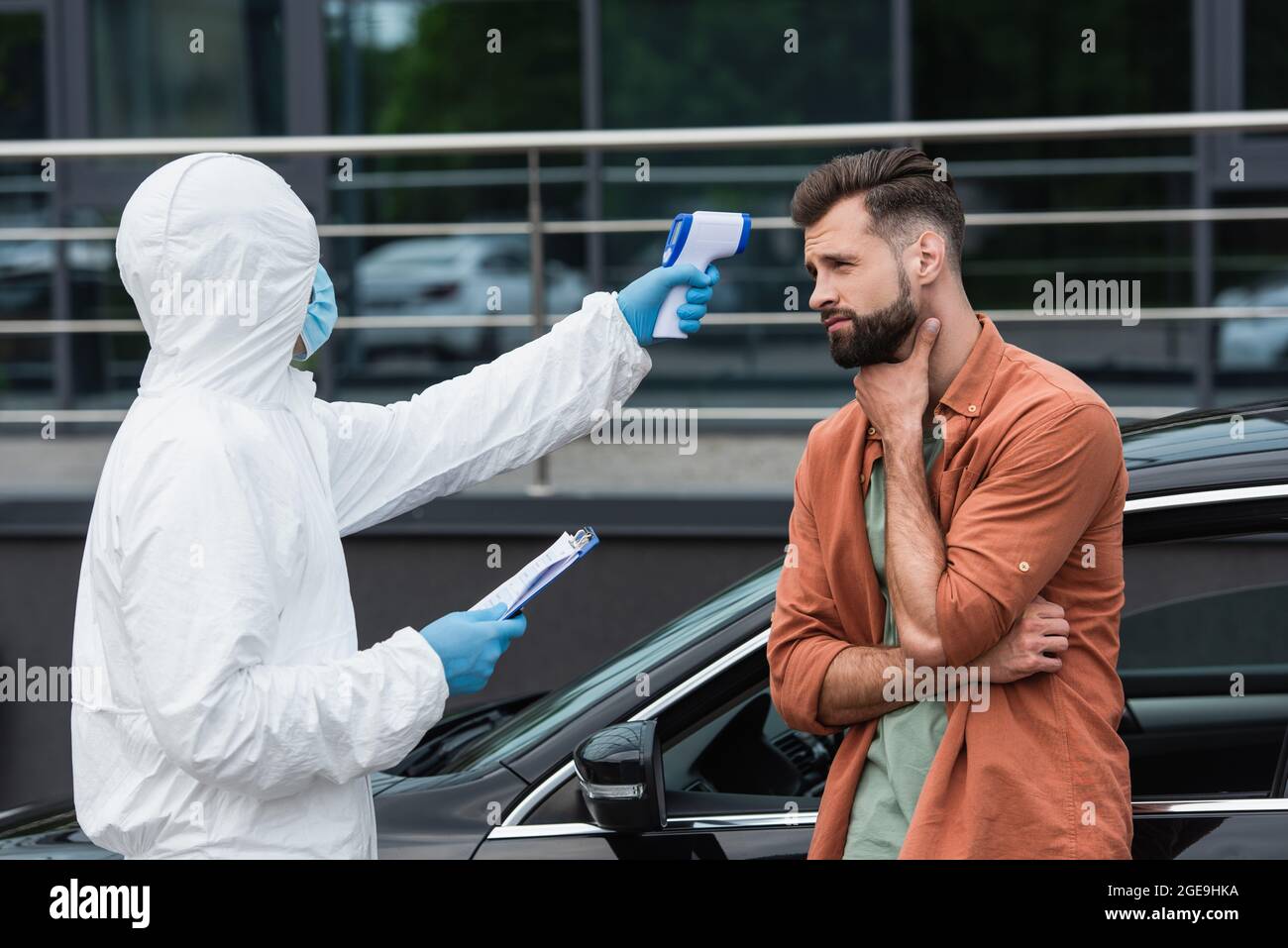 Medical worker checking temperature of sick driver near car outdoors ...