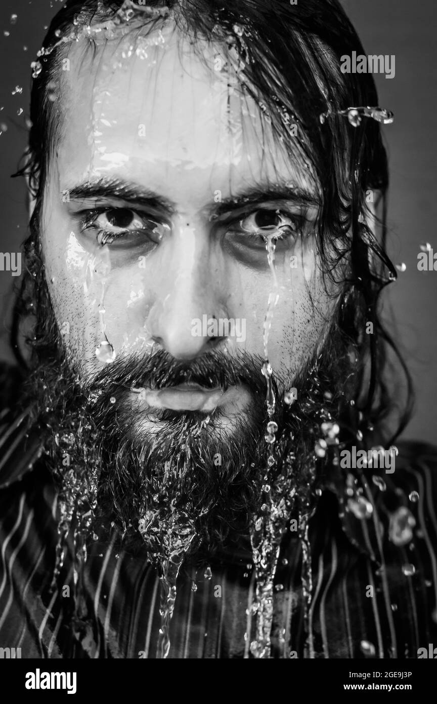 Black and white very close-up portrait of a young bearded man with an ...