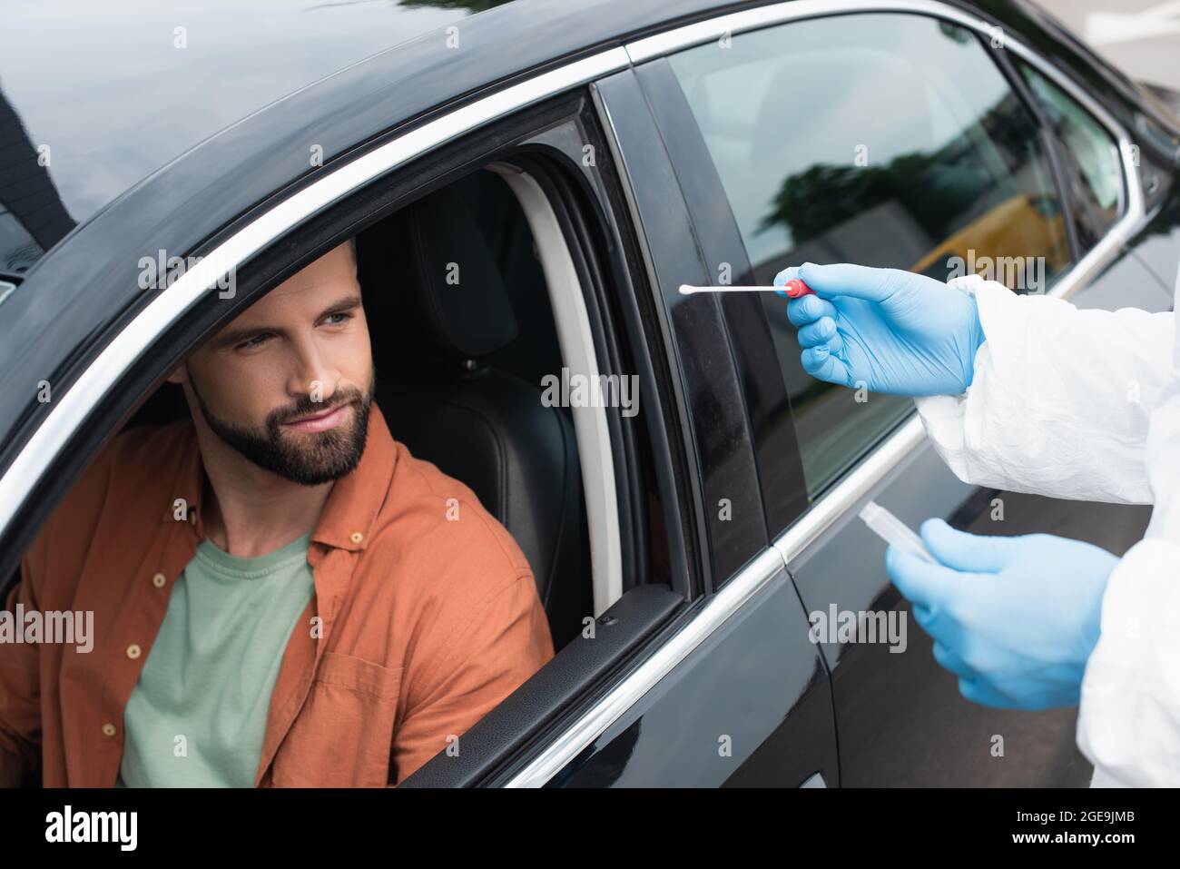 Medical worker holding cotton swab of pcr test near driver in car Stock ...