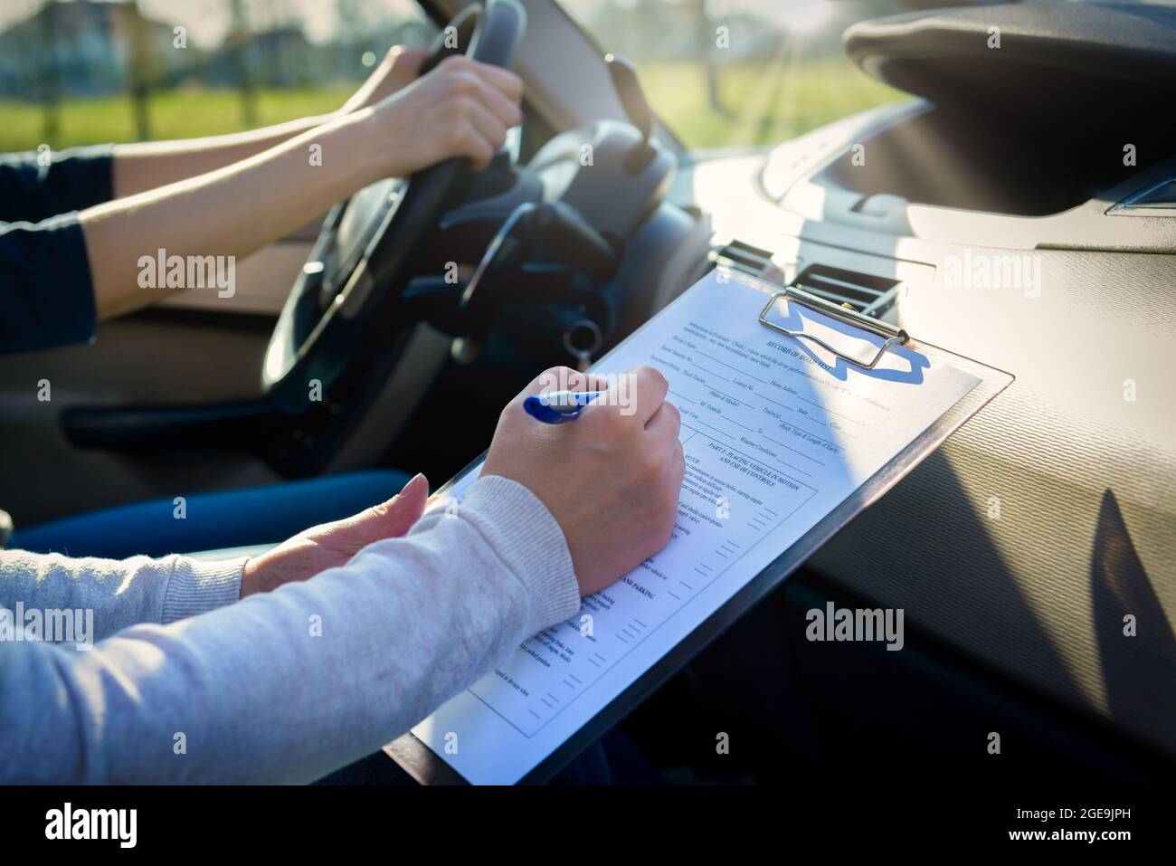 Examiner filling in driver's license road test form sitting with her ...