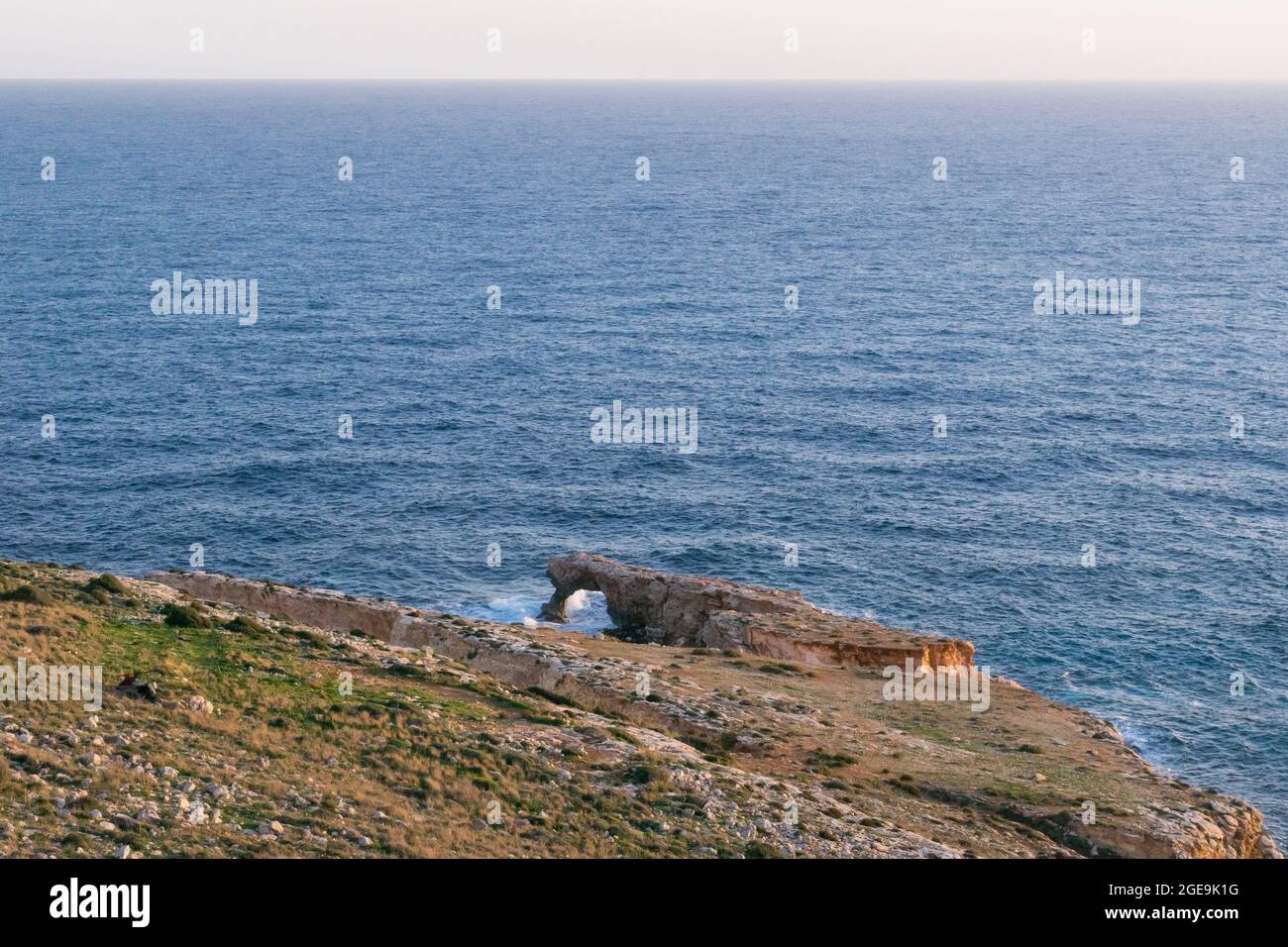 Natural sea arch formed by sea erosion at the tip of a headland called ...