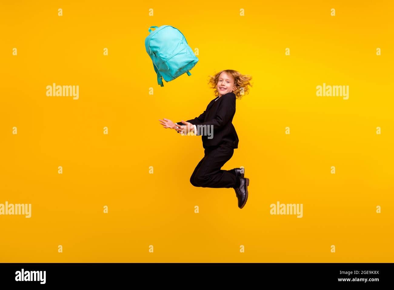 Photo of funny schoolboy jump throw catch rucksack enjoy flight wear ...