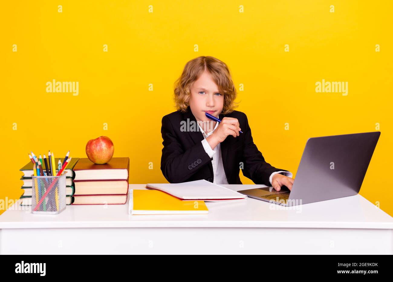 Photo of intelligent pensive schoolkid sit hold pen write homework wear ...