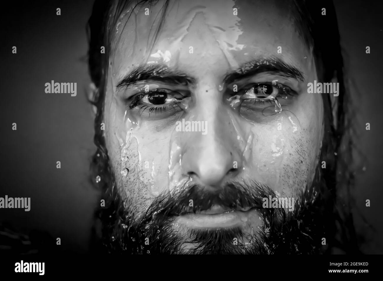 Black and white very close-up portrait of a young bearded man with ...