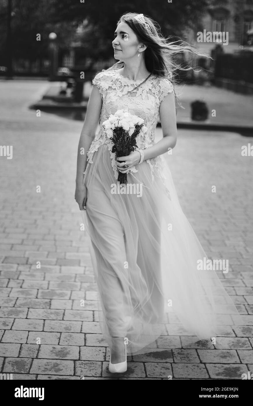 Beautiful happy bride in stylish vintage dress walking in sunny street ...