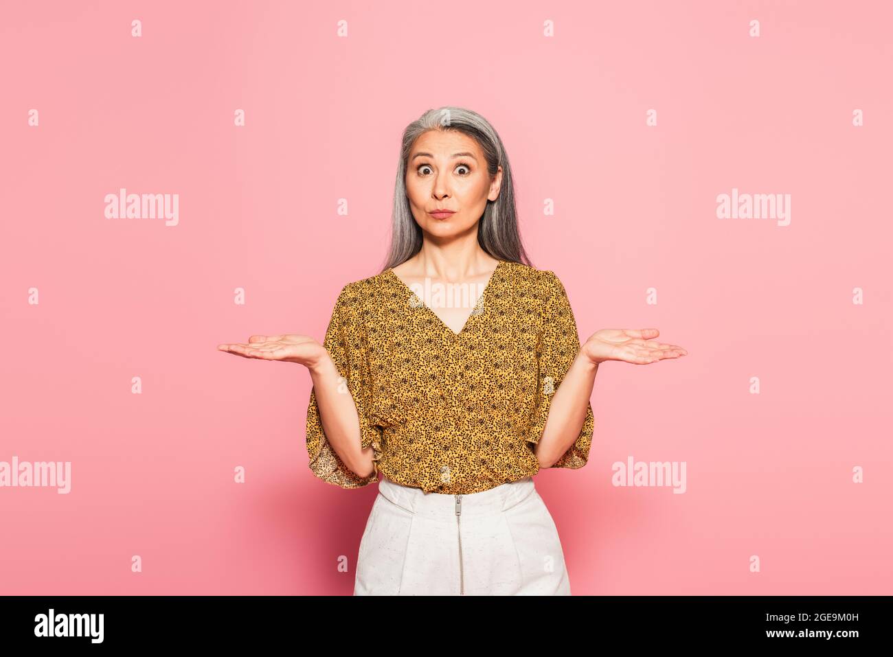 discouraged woman pointing with hands while looking at camera on pink ...
