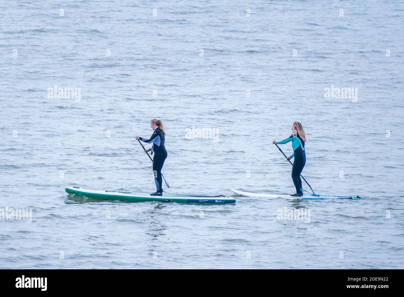 Two women paddle boarding on the sea Stock Photo - Alamy