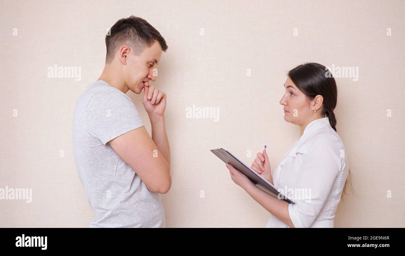 Female doctor talking to a male patient and fills out a document ...