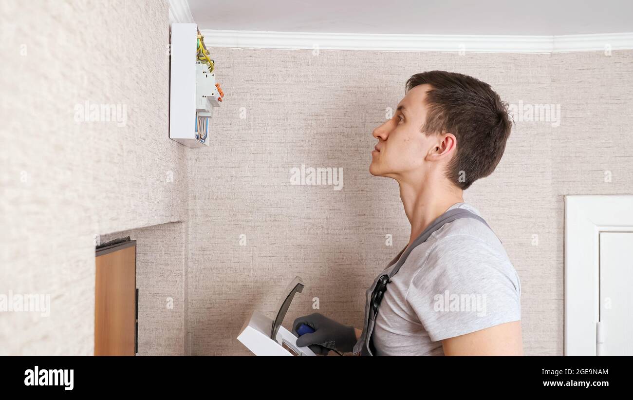 Skilled craftsman covers switchboard with case in hallway Stock Photo ...