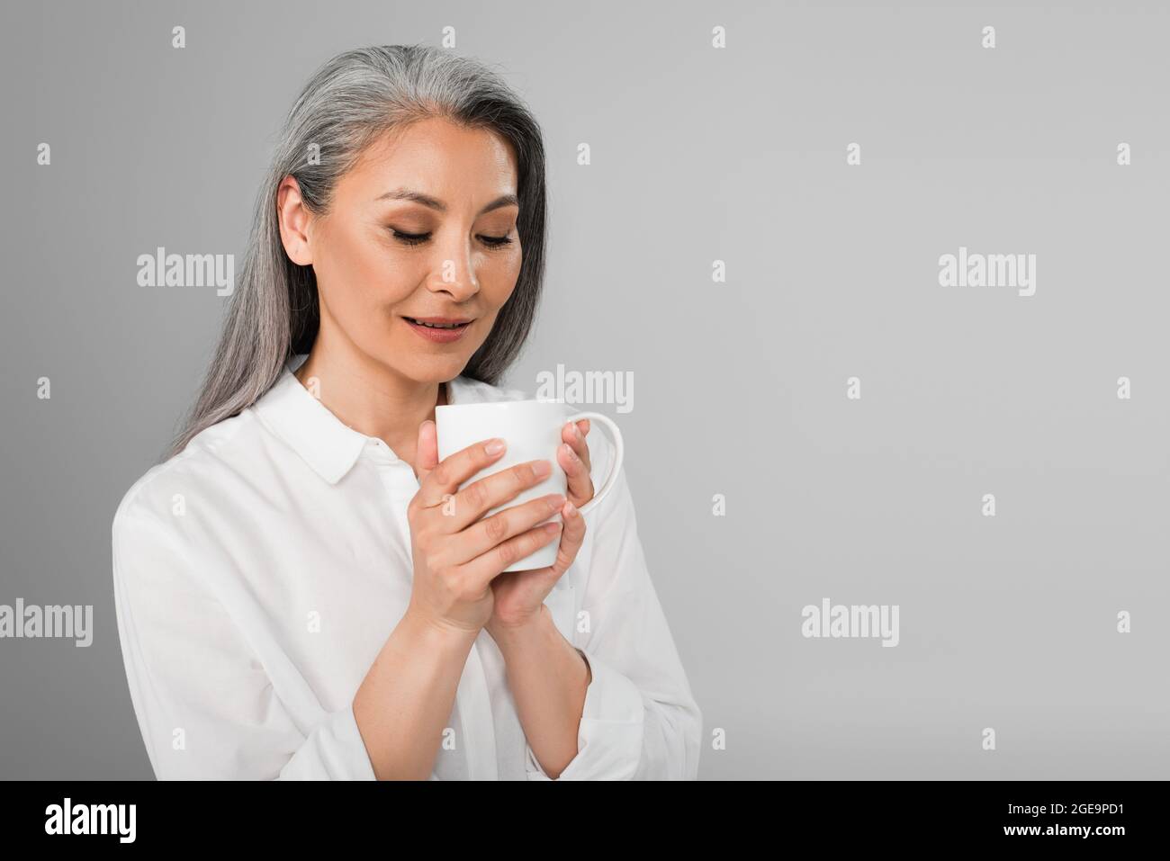 middle aged, grey haired woman holding white cup with tea isolated on ...