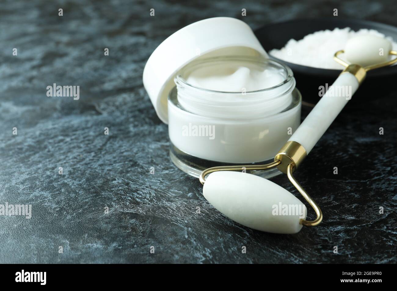 Skin care concept with face roller on black smokey table Stock Photo ...