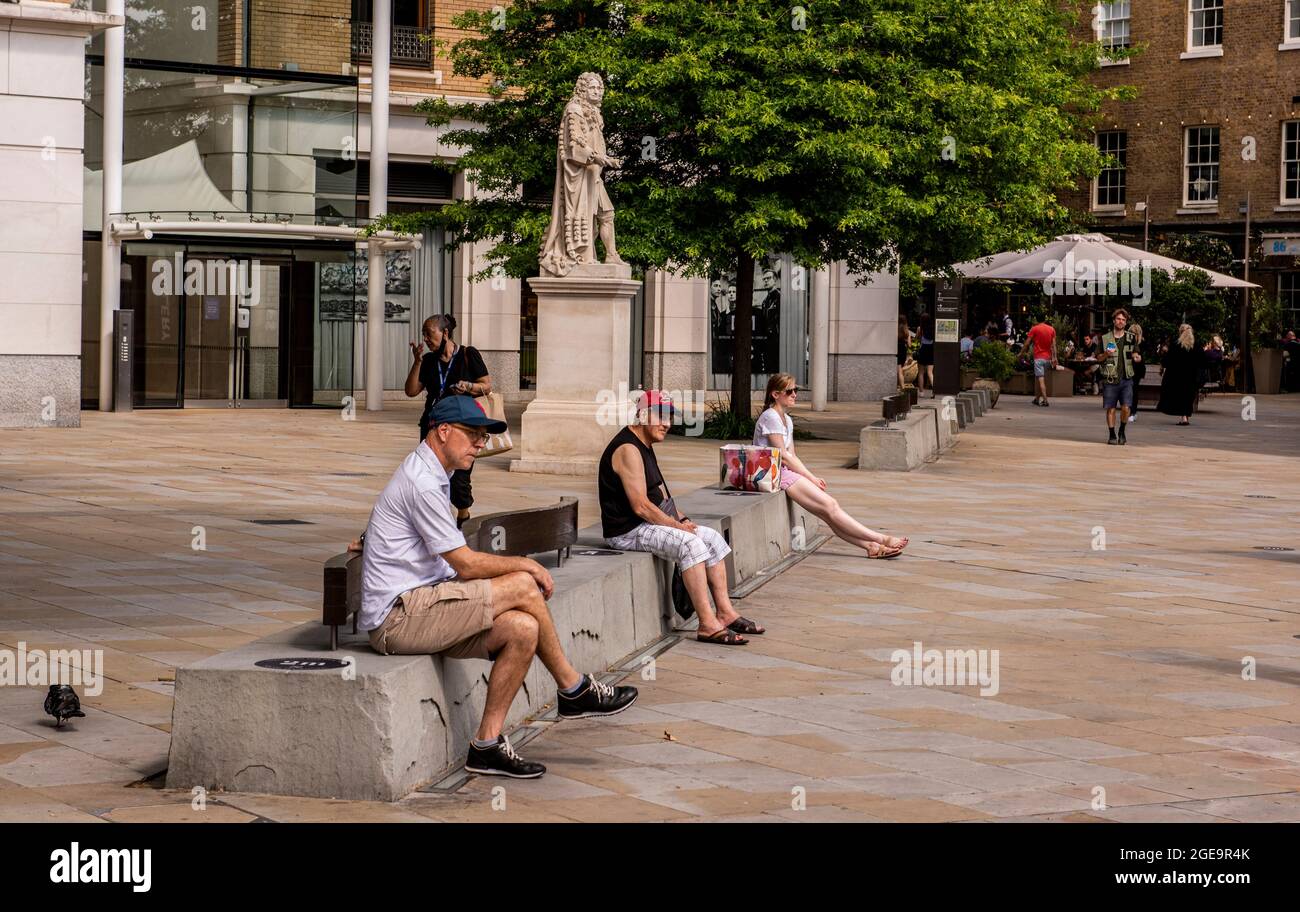 People sit in summer clothes by the statue of Sir Hans Sloane in Sloane ...