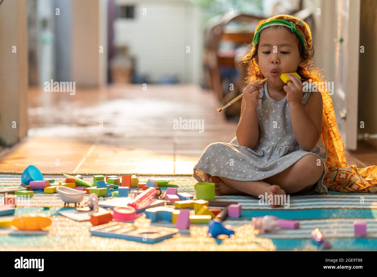 Little girl sitting on a mat playing wooden building blocks in the ...