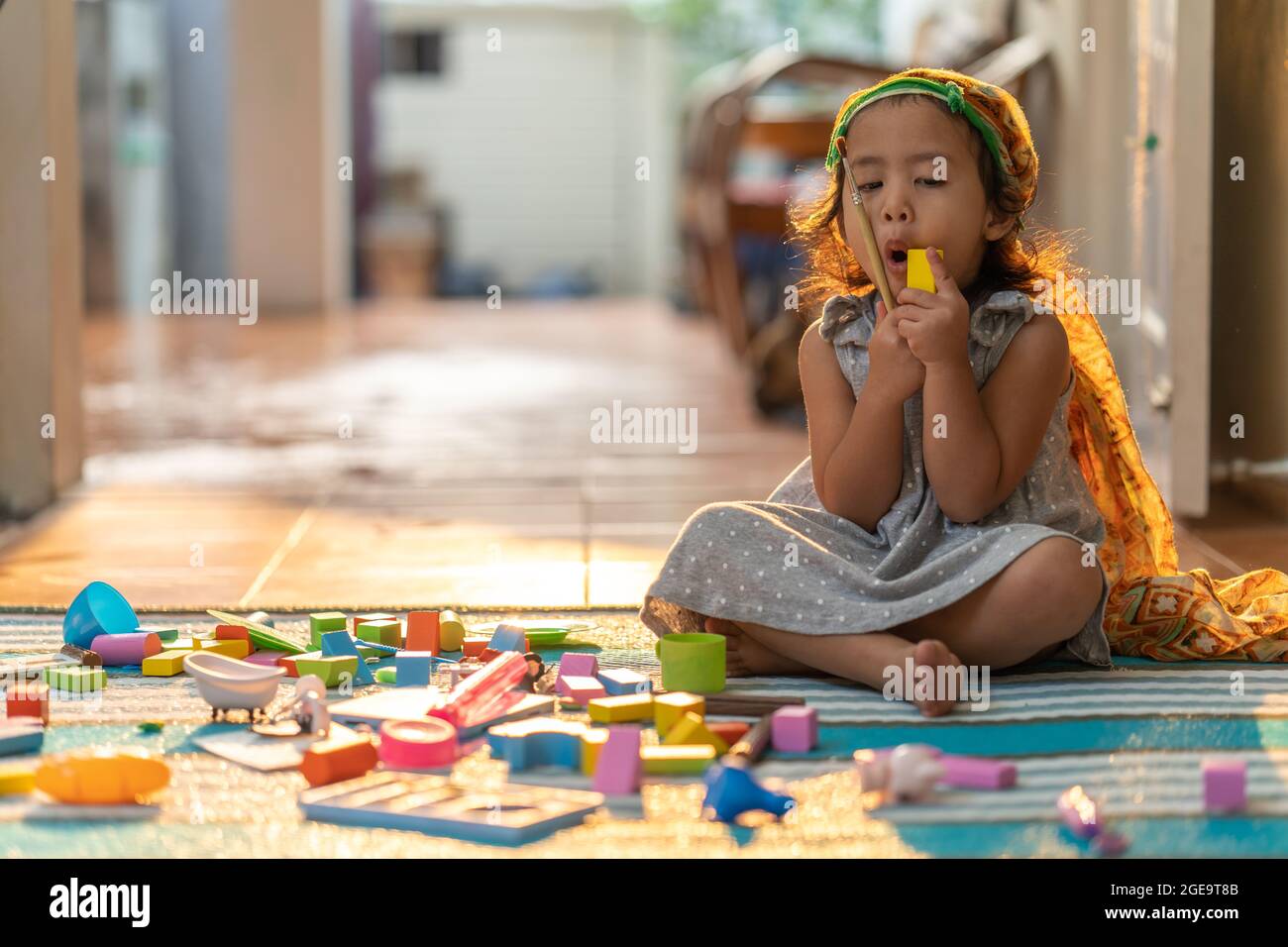 Little girl sitting on a mat playing wooden building blocks in the ...