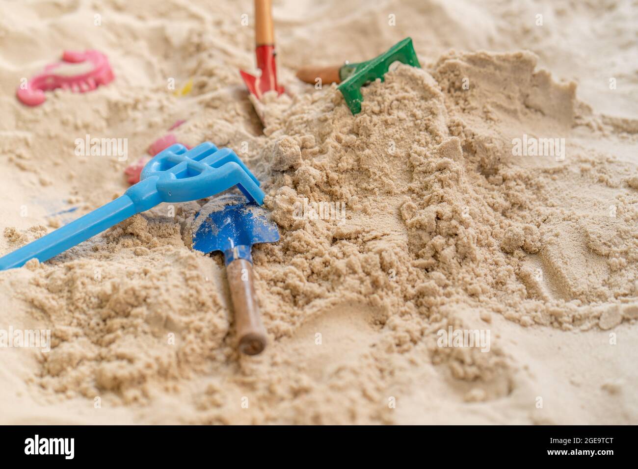 Little girl playing with plastic children toys in a sandpit outdoor ...