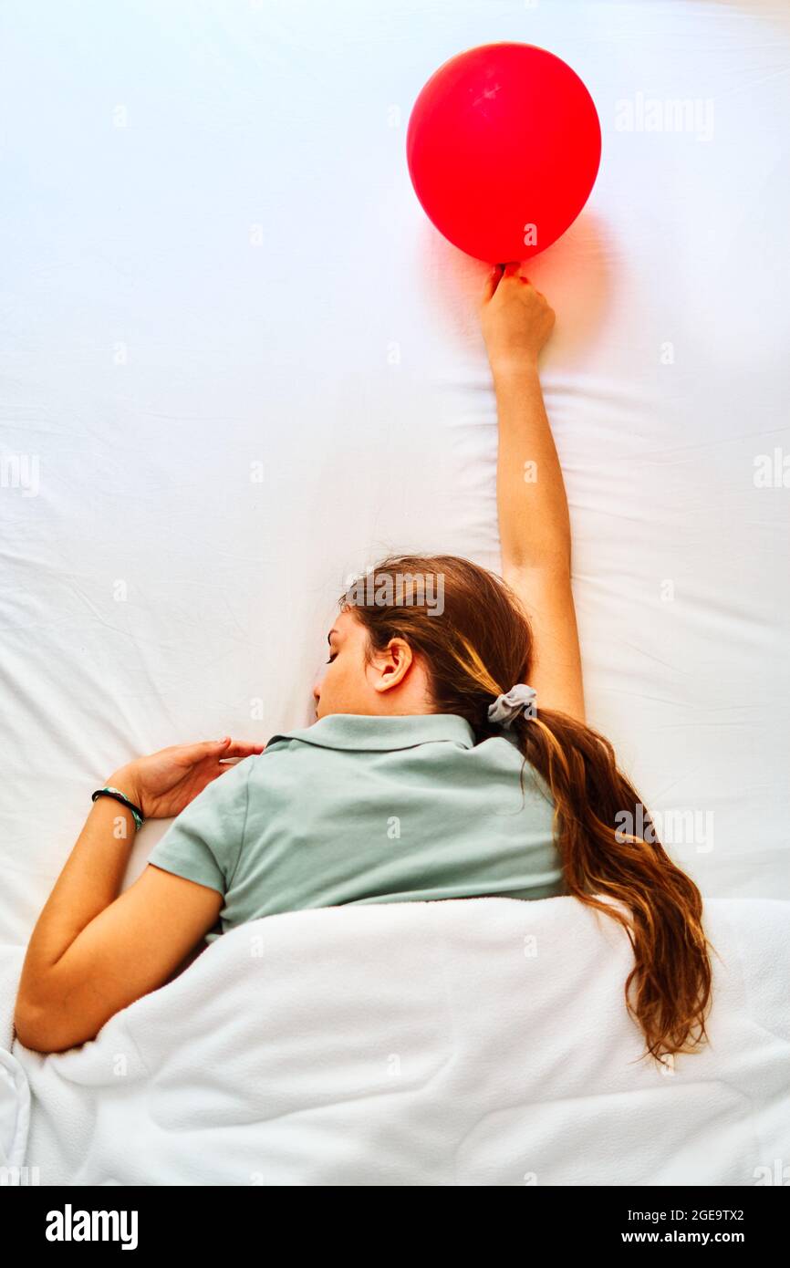 From above back view of tired young female with red balloon in hand ...