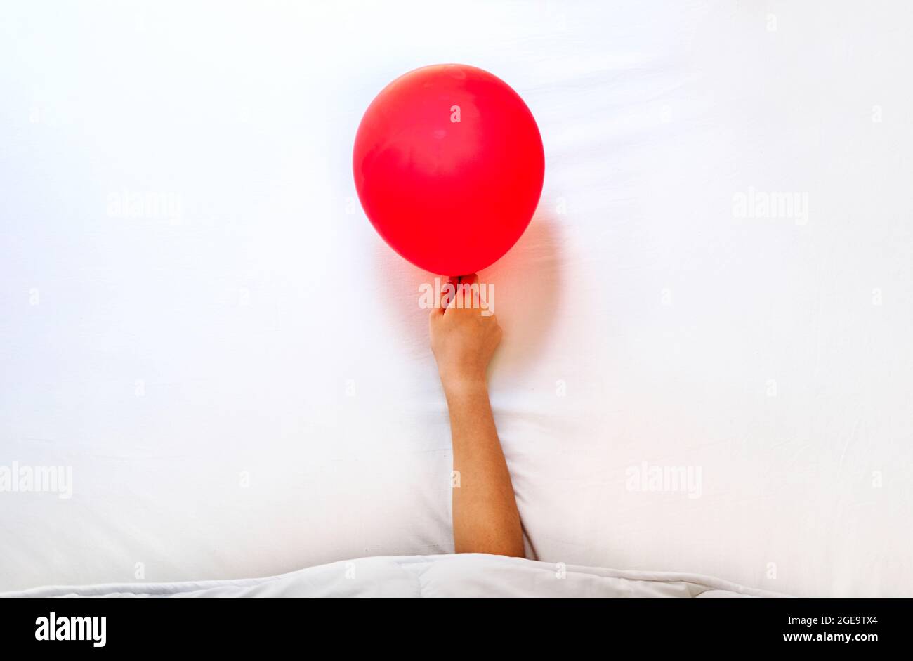 Cropped unrecognizable tired person with red balloon in hand sleeping ...