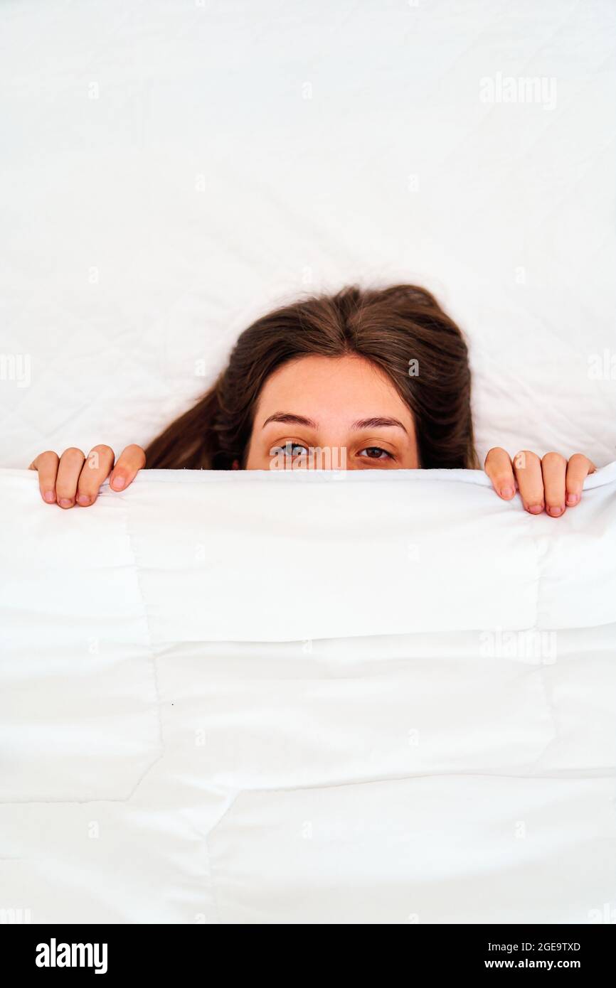 From above of lazy young female looking at camera covering half of face ...