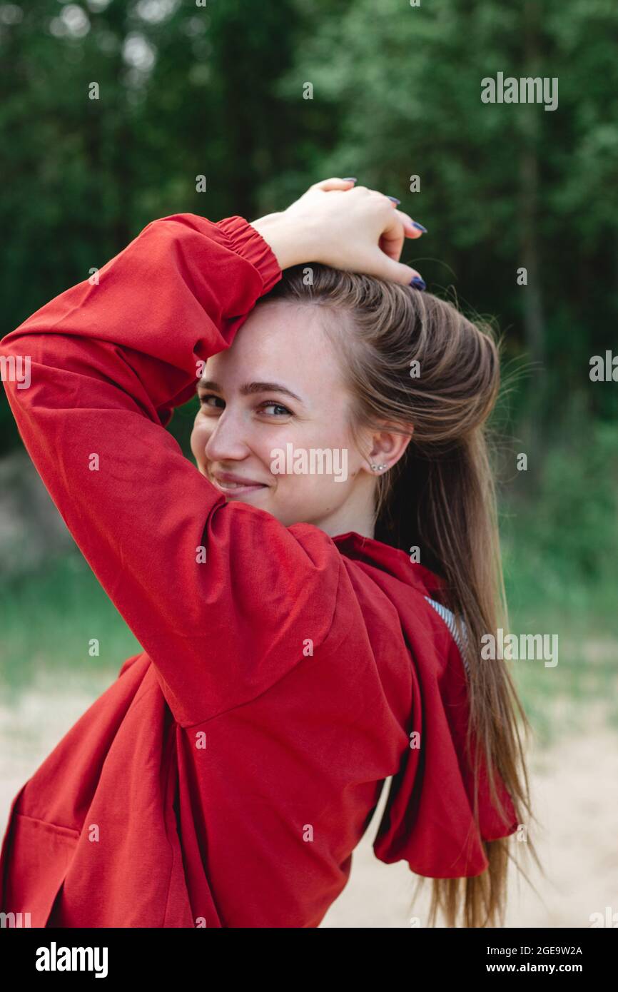 Candid portrait of a young caucasian woman in red clothes playing with ...