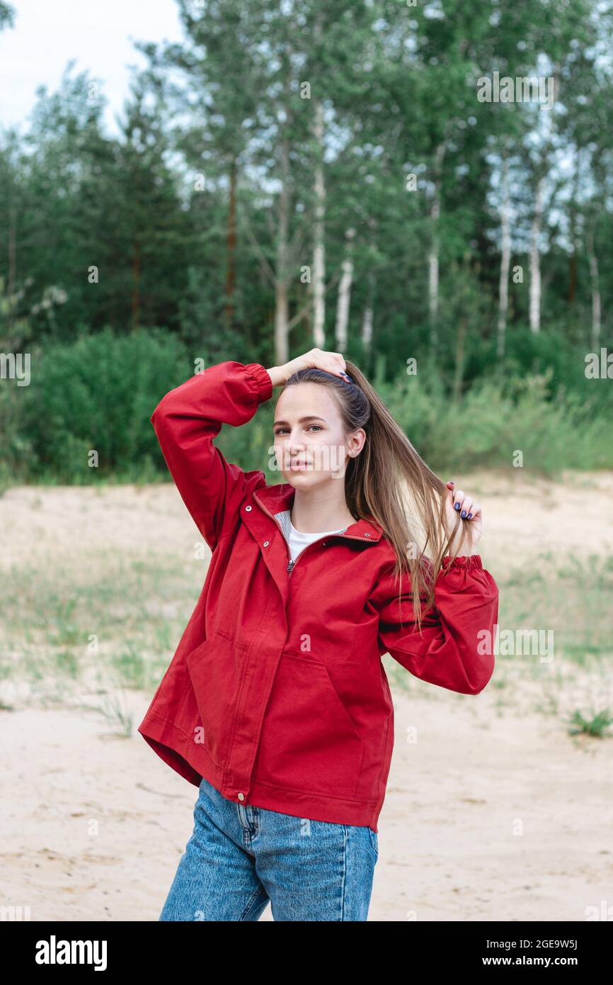 Candid portrait of a young caucasian woman in red clothes playing with ...