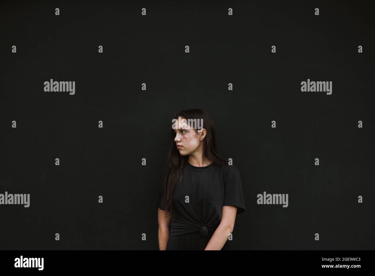 Anonymous trendy female standing on background of black wall of ...
