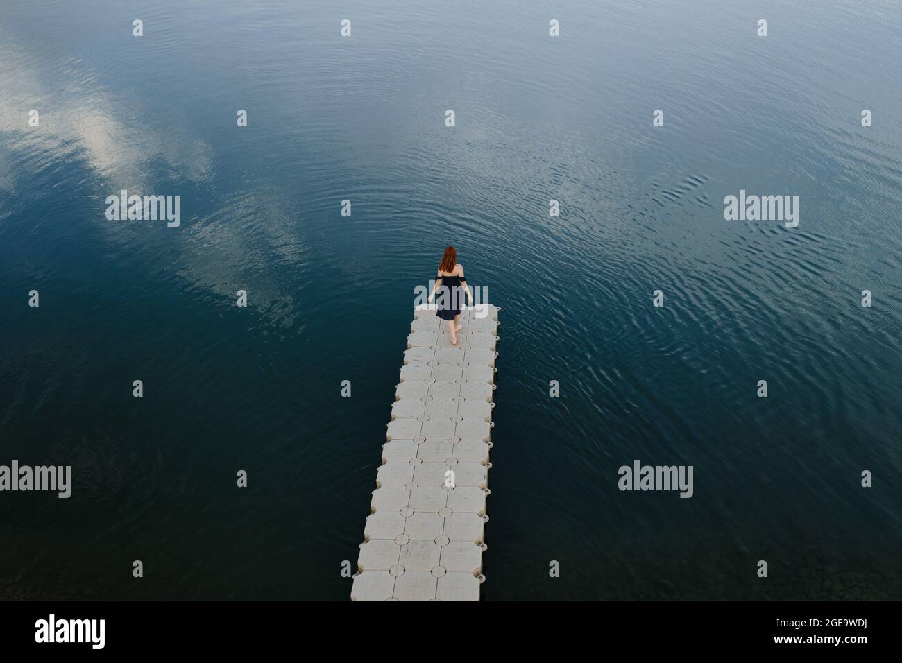From above remote view of female standing on edge of quay near calm ...
