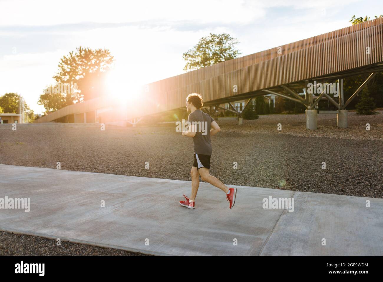 Side view of active male athlete running along asphalt walkway during ...