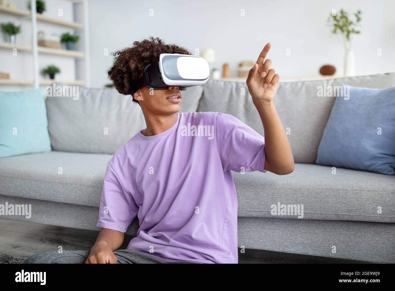 Black teen guy in VR headset exploring virtual reality at home ...