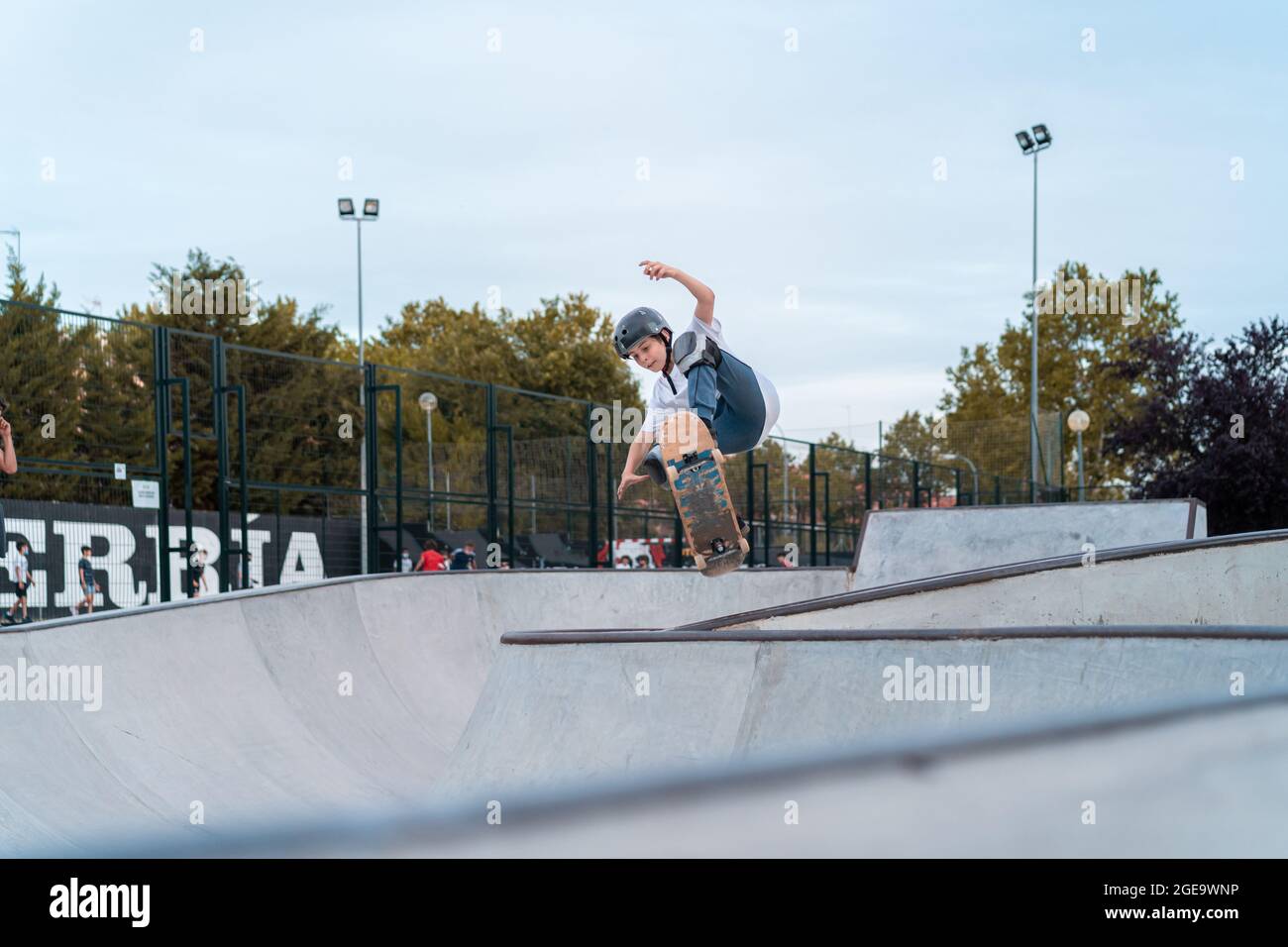 Teenage boy jumping with skateboard and showing stunt on ramp in skate ...