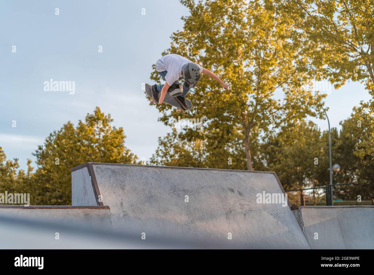 Teenage boy jumping with skateboard and showing stunt on ramp in skate ...