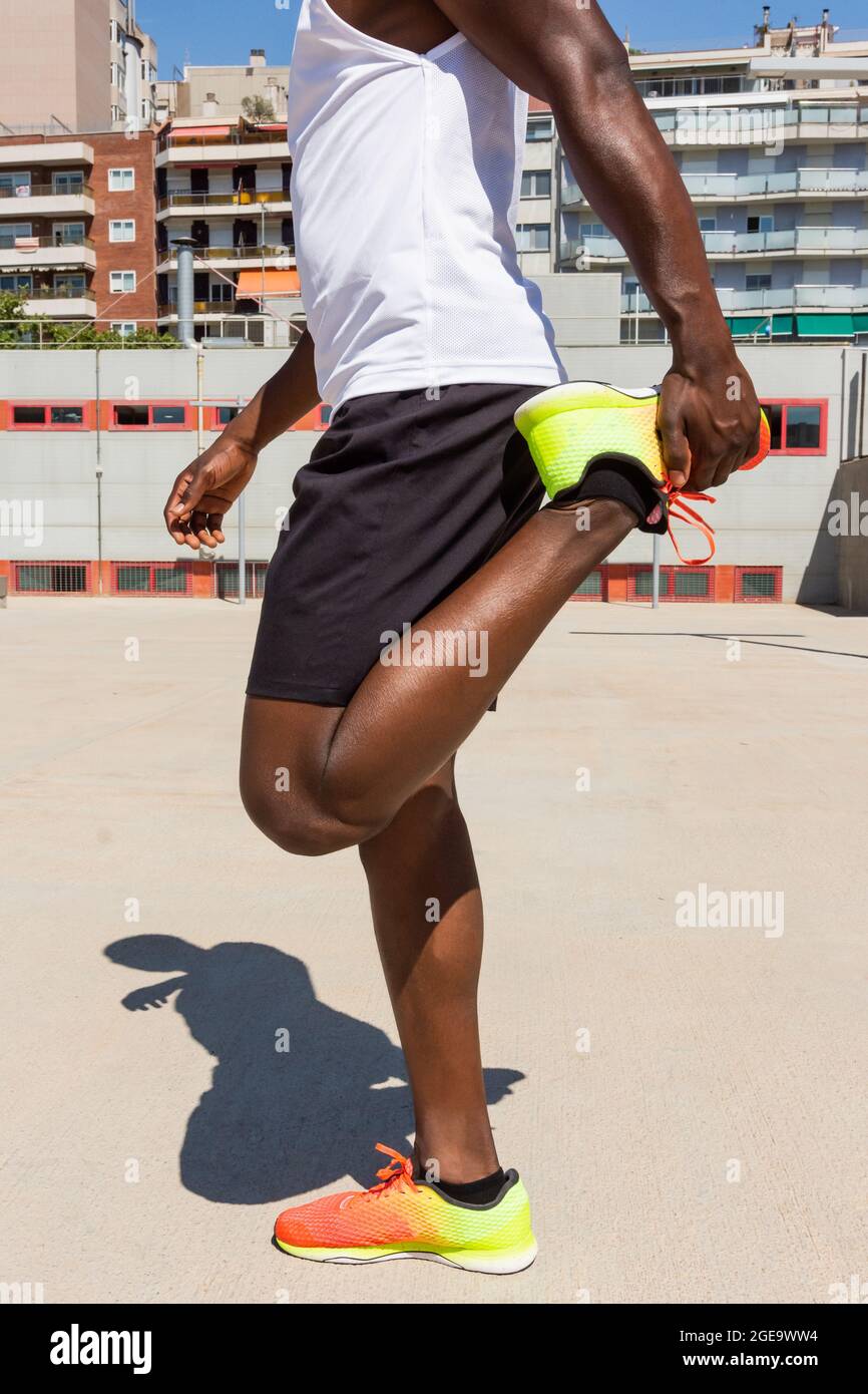 Side view of fit black male athlete stretching legs while warming up ...