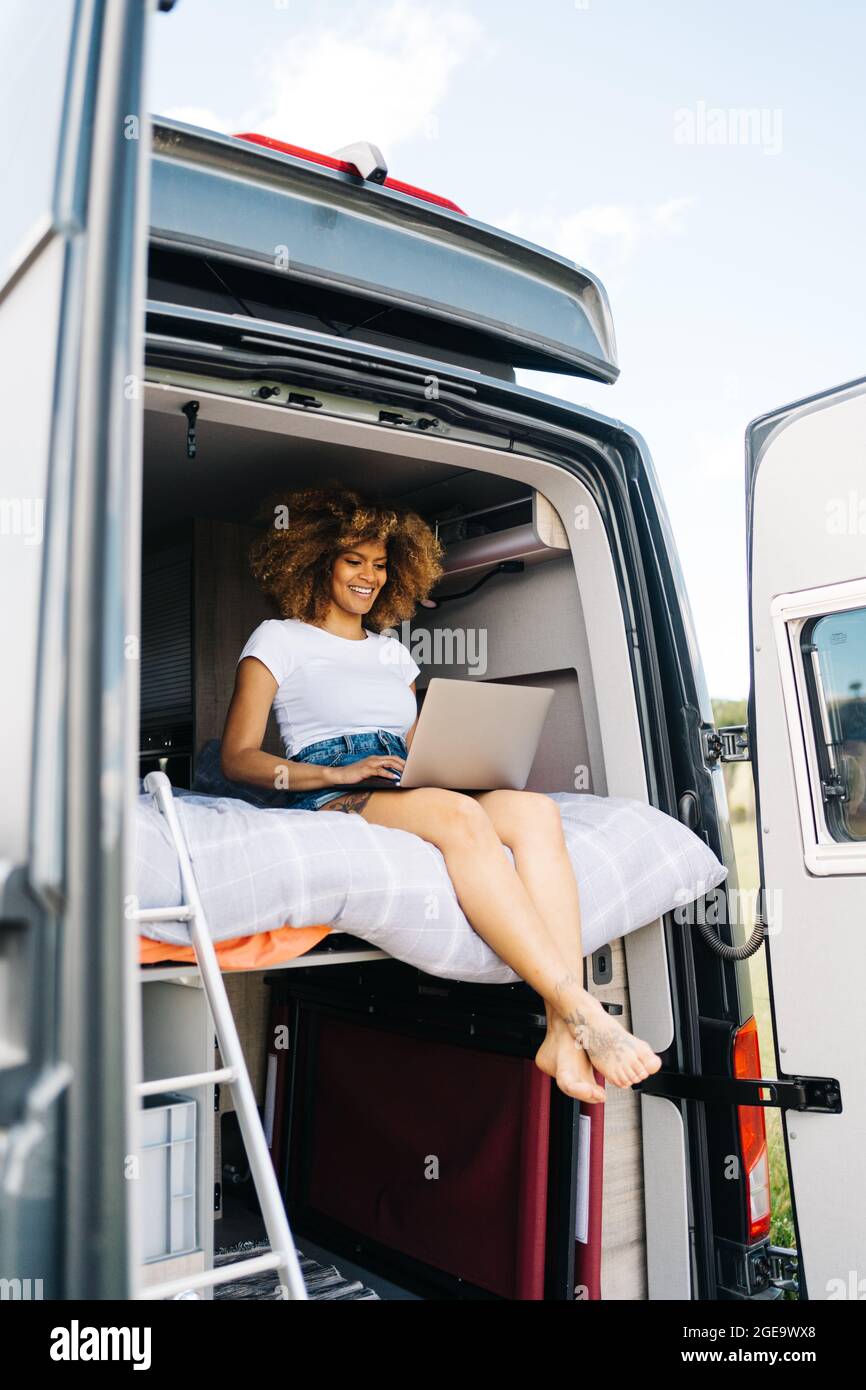 Young African American female traveler with curly hair watching movie ...
