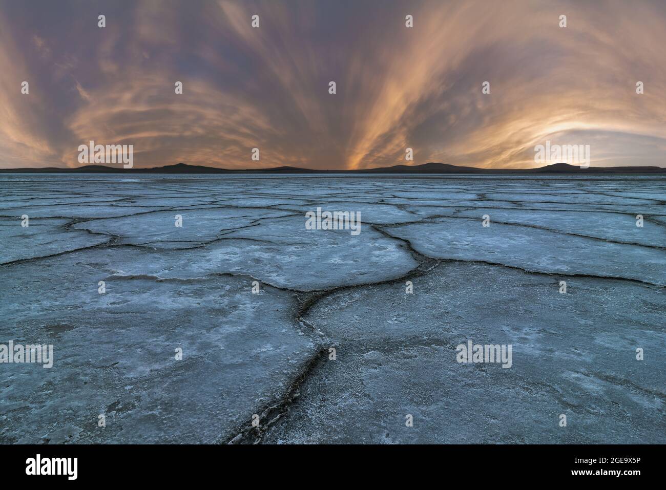 Amazing scenery of salty lagoon with dried rough ground under sundown ...