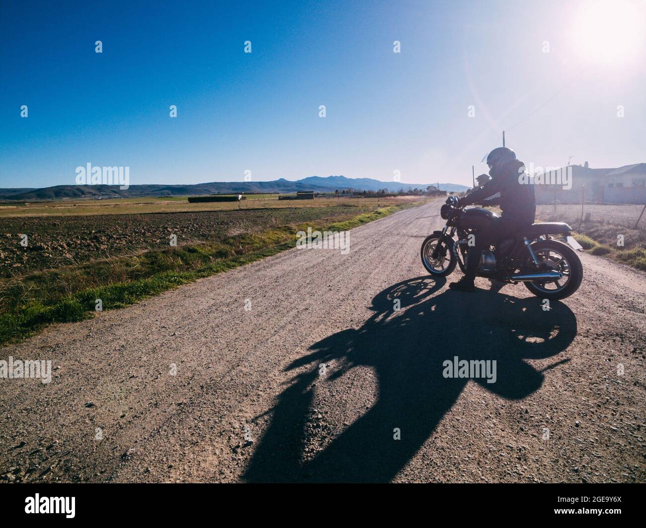 Side view person driving motorbike on rural road in sunlight in ...