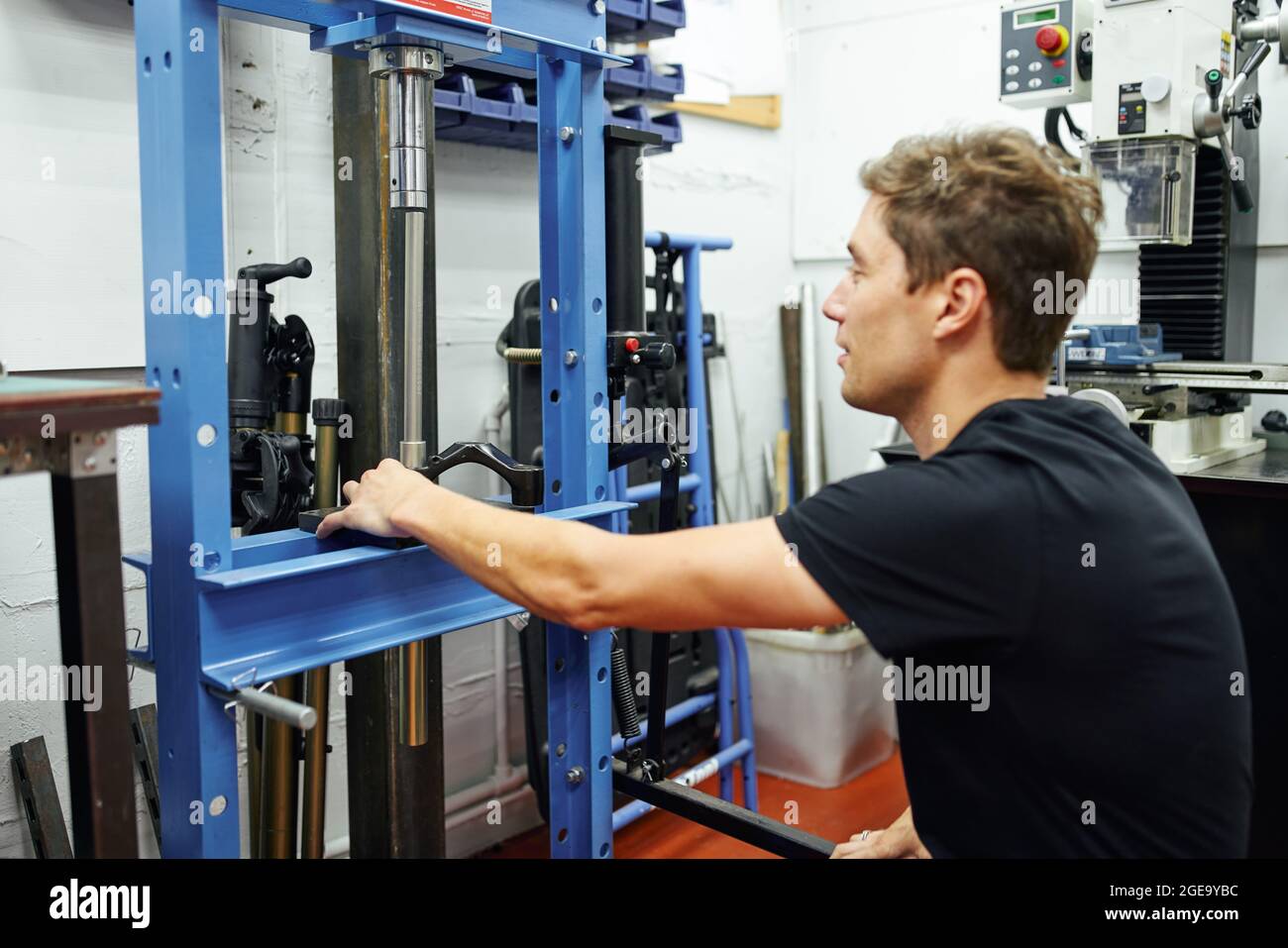 Side view of adult man using hydraulic press while working in modern ...